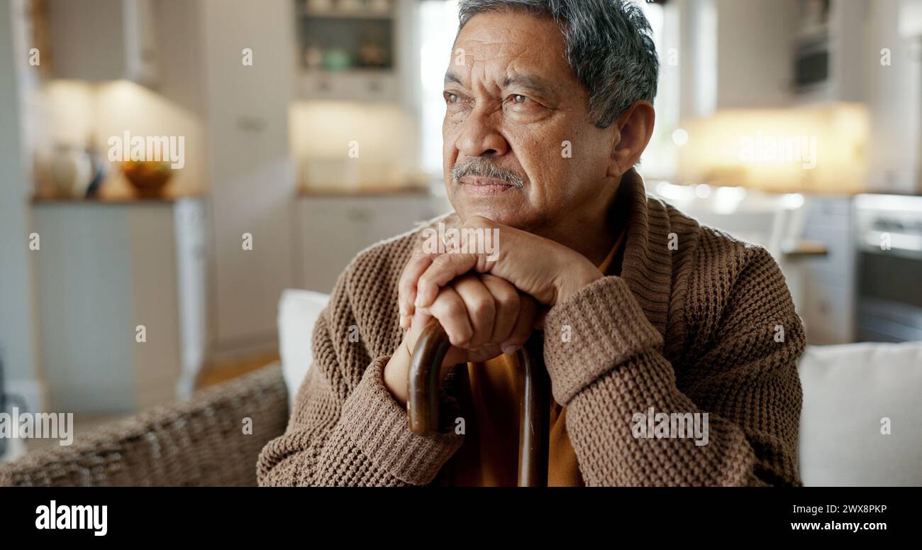 Depression, nostalgia and a senior man with a cane on a sofa in the living room of his ...