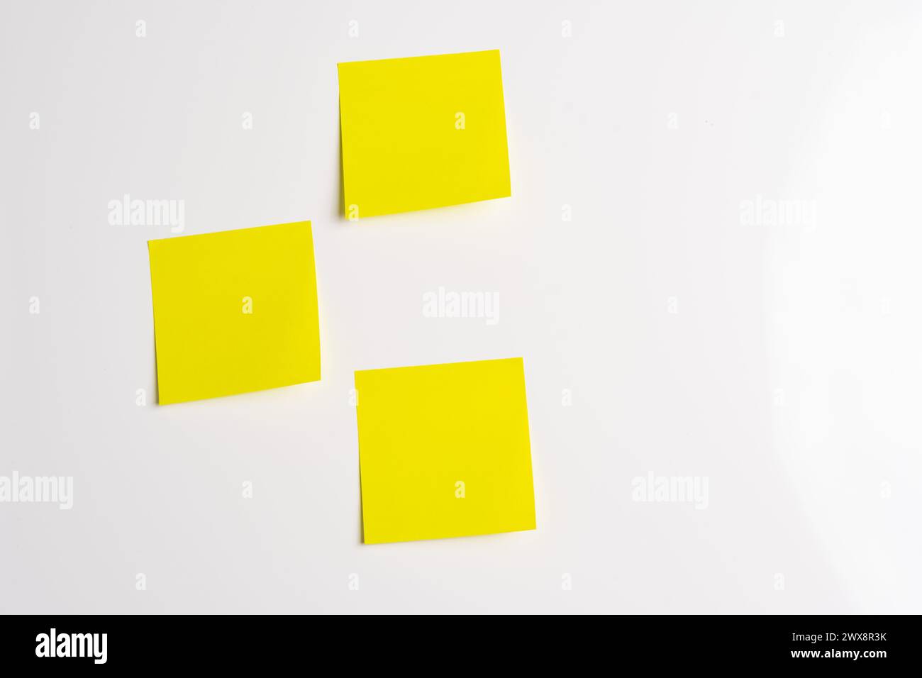 Three blank yellow sticky notes posted on an isolated white background ...