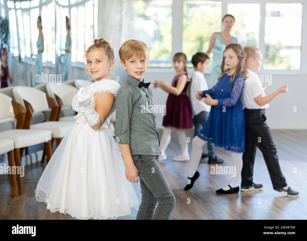 Interested preteen pupils rehearsing twist dance steps in classroom ...