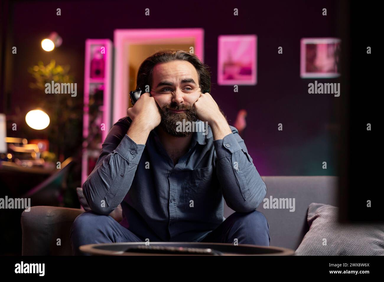 Depressed man looking saddened at TV display while playing videogames ...