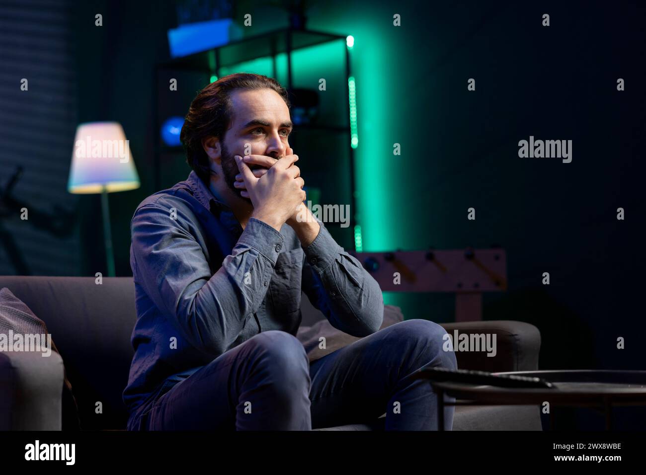 Man covering mouth in shock watching horror movie on streaming services ...