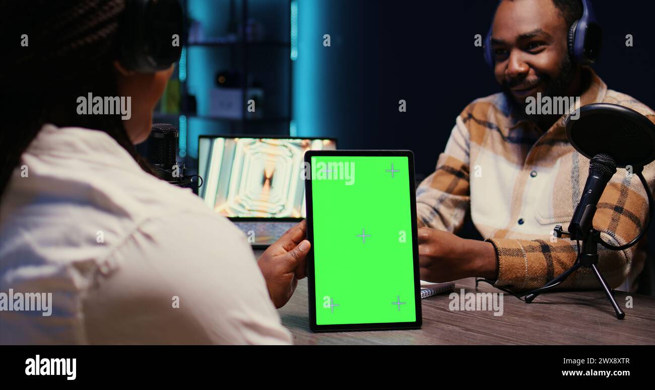 Online show host holding green screen tablet while listening to guest ...
