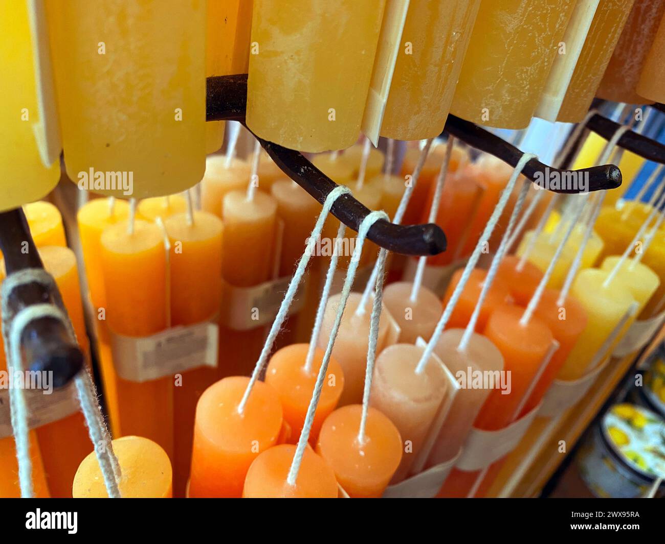 Handmade orange and yellow artisanal candles displayed on a rack Stock ...