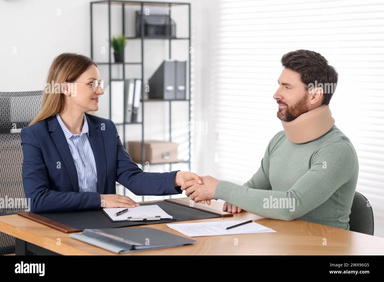 Lawyer shaking hands with injured client in office Stock Photo - Alamy