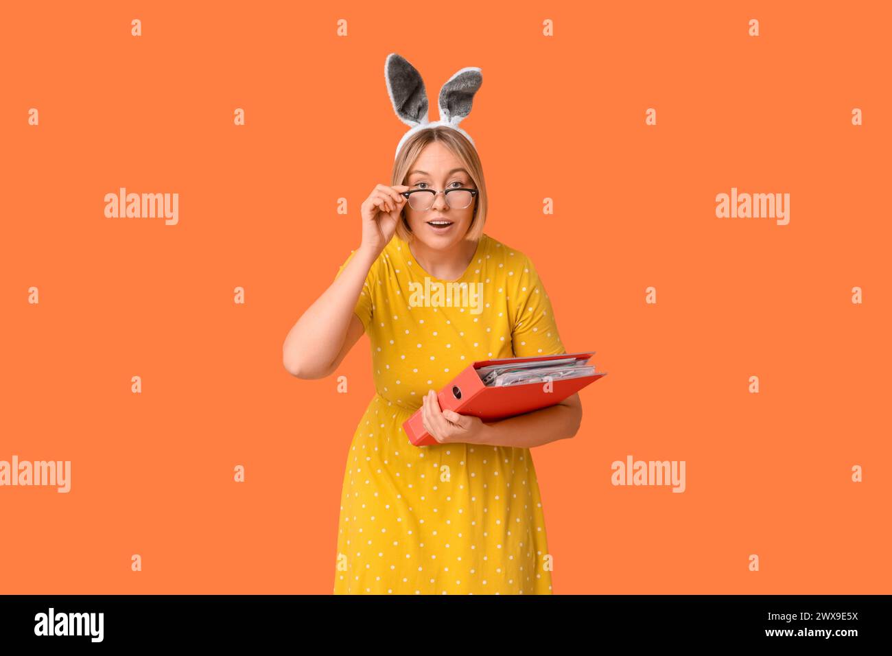 Surprised adult female secretary in bunny ears with documents folder on ...