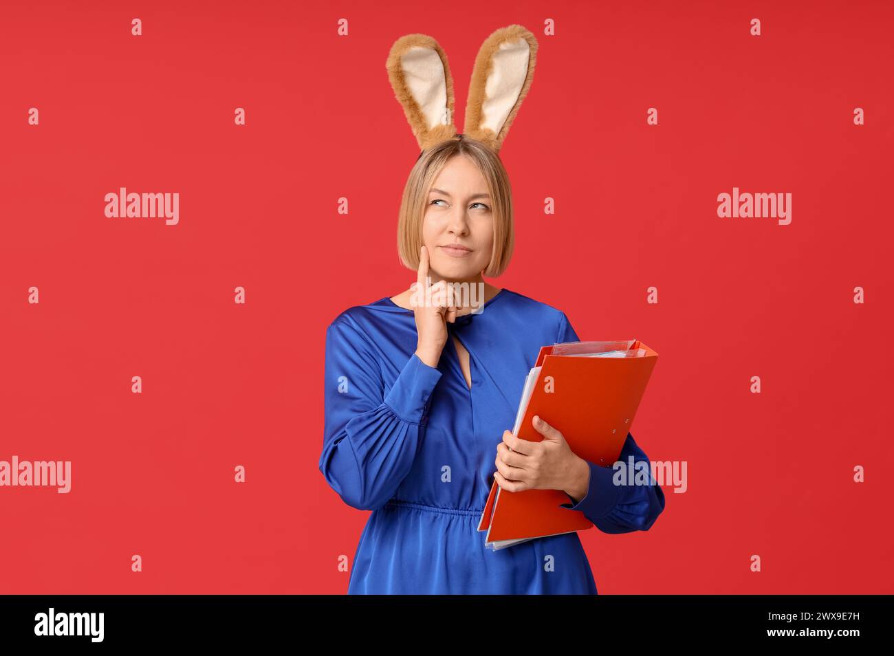 Thoughtful adult female secretary in bunny ears with documents folder ...