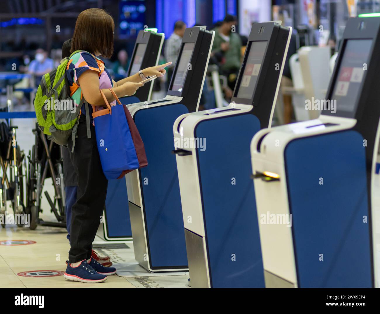 A woman using self check-in kiosks in airport terminal Stock Photo - Alamy