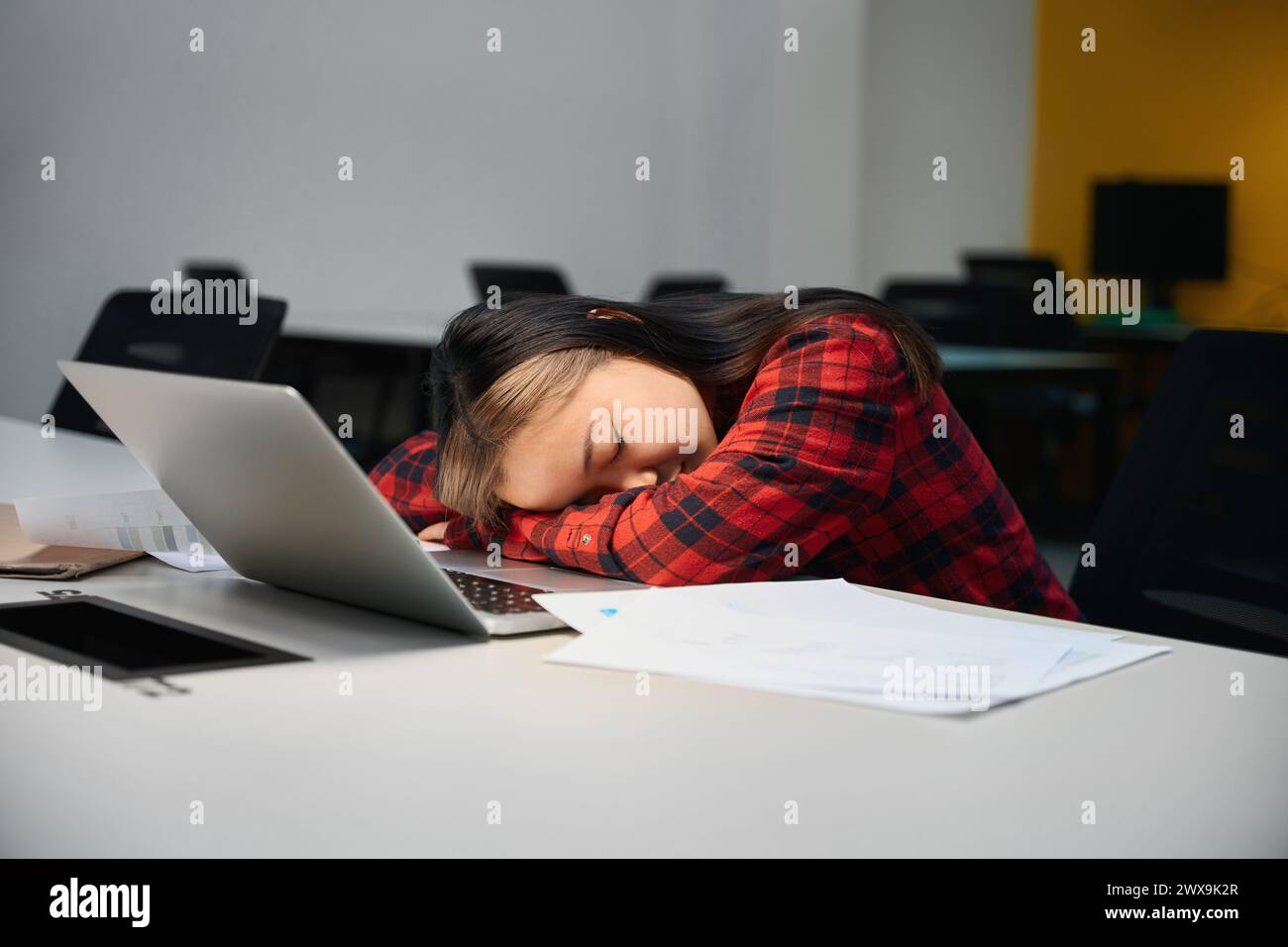 Tired asian female IT employee sleeping at working desk in coworking ...