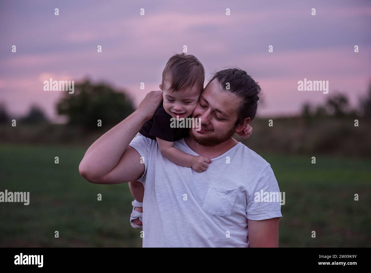 Heartwarming scene of diversity father carrying smiling son on ...