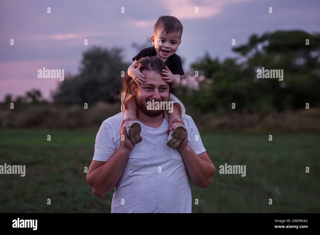 Diversity father with beard carrying son on shoulders shares tender ...