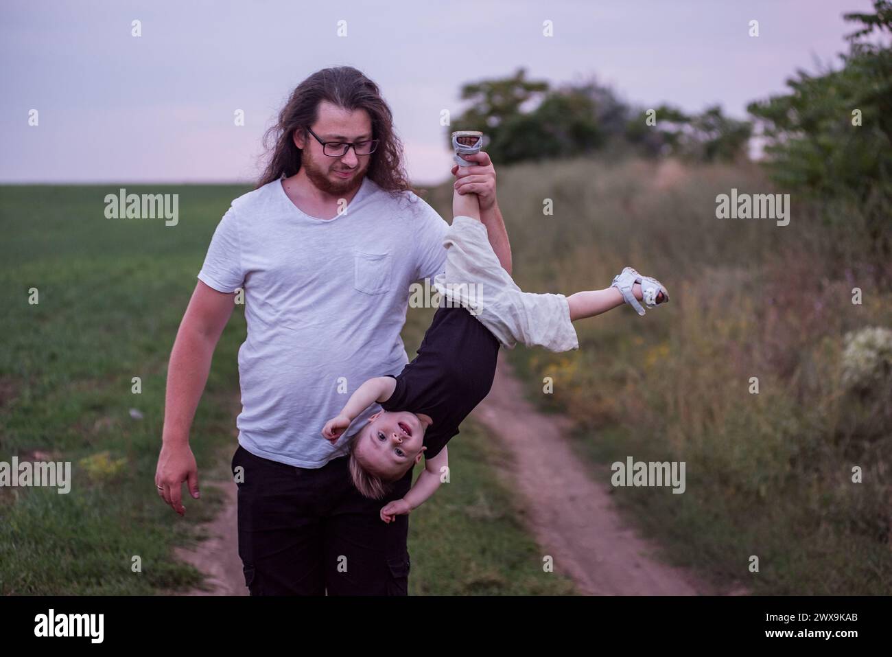Diversity father holding little son upside down playfully indicates his ...