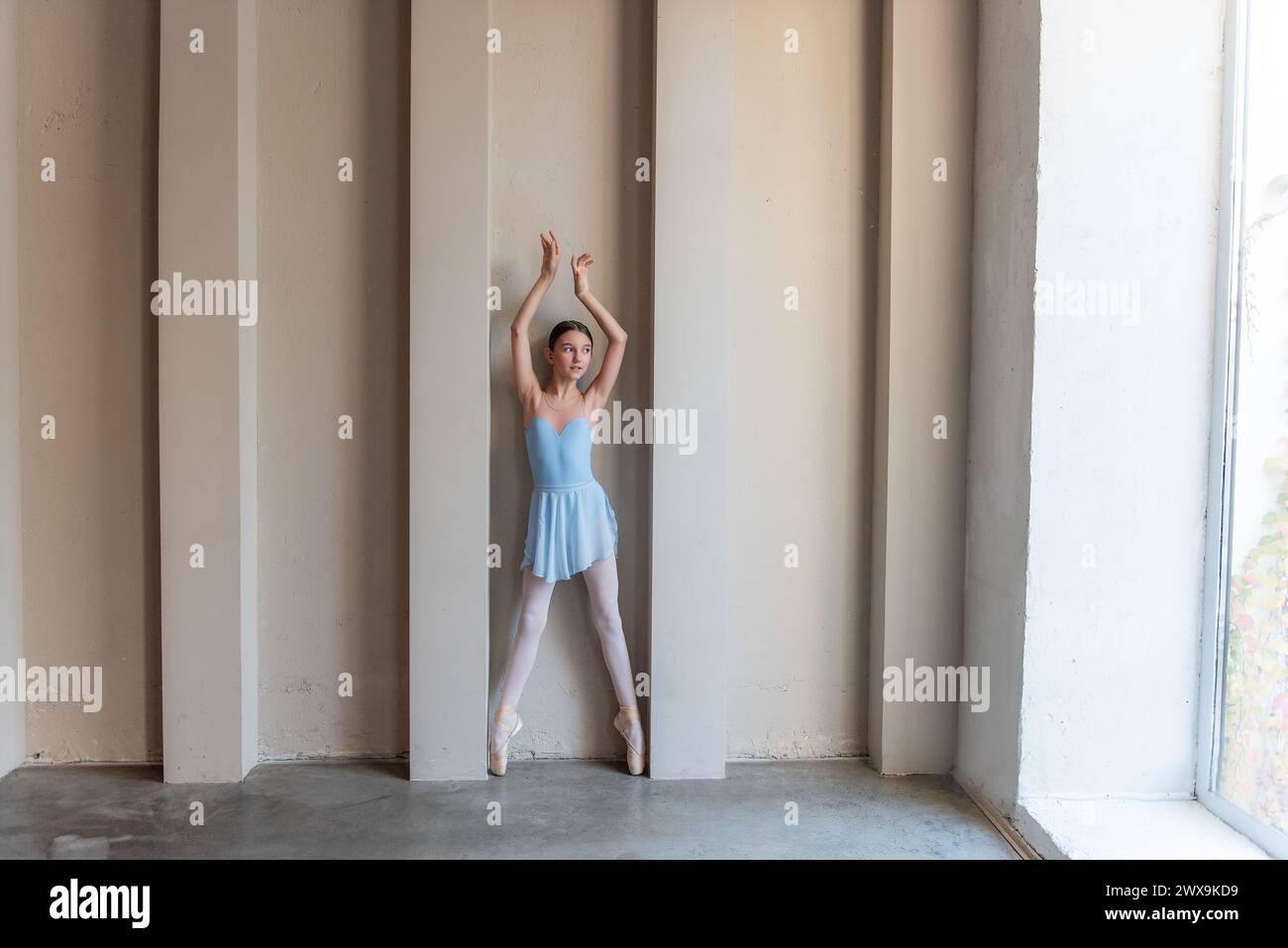 Elegant Young Ballerina In Blue Costume Stands En Pointe Arms Raised