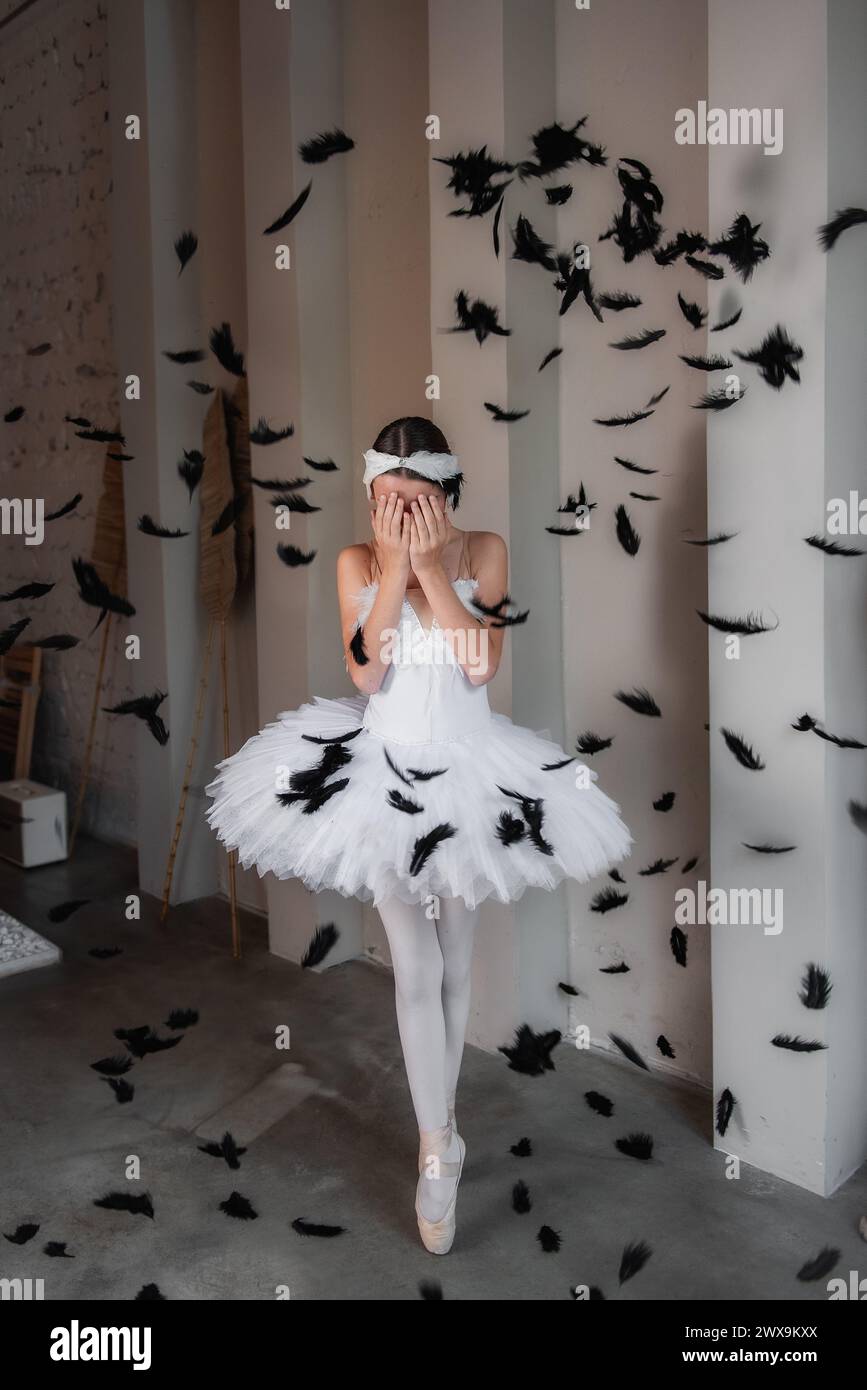 Dramatic young ballerina in white tutu, tiara stands on pointe ...