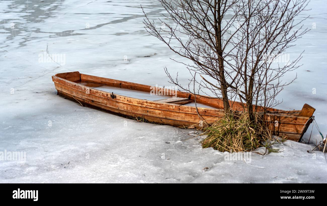 spring landscape with a wooden boat frozen in ice, abandoned boats on ...