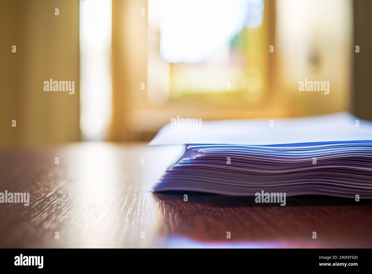A pristine desk adorned with neatly stacked white A4 papers, creating ...