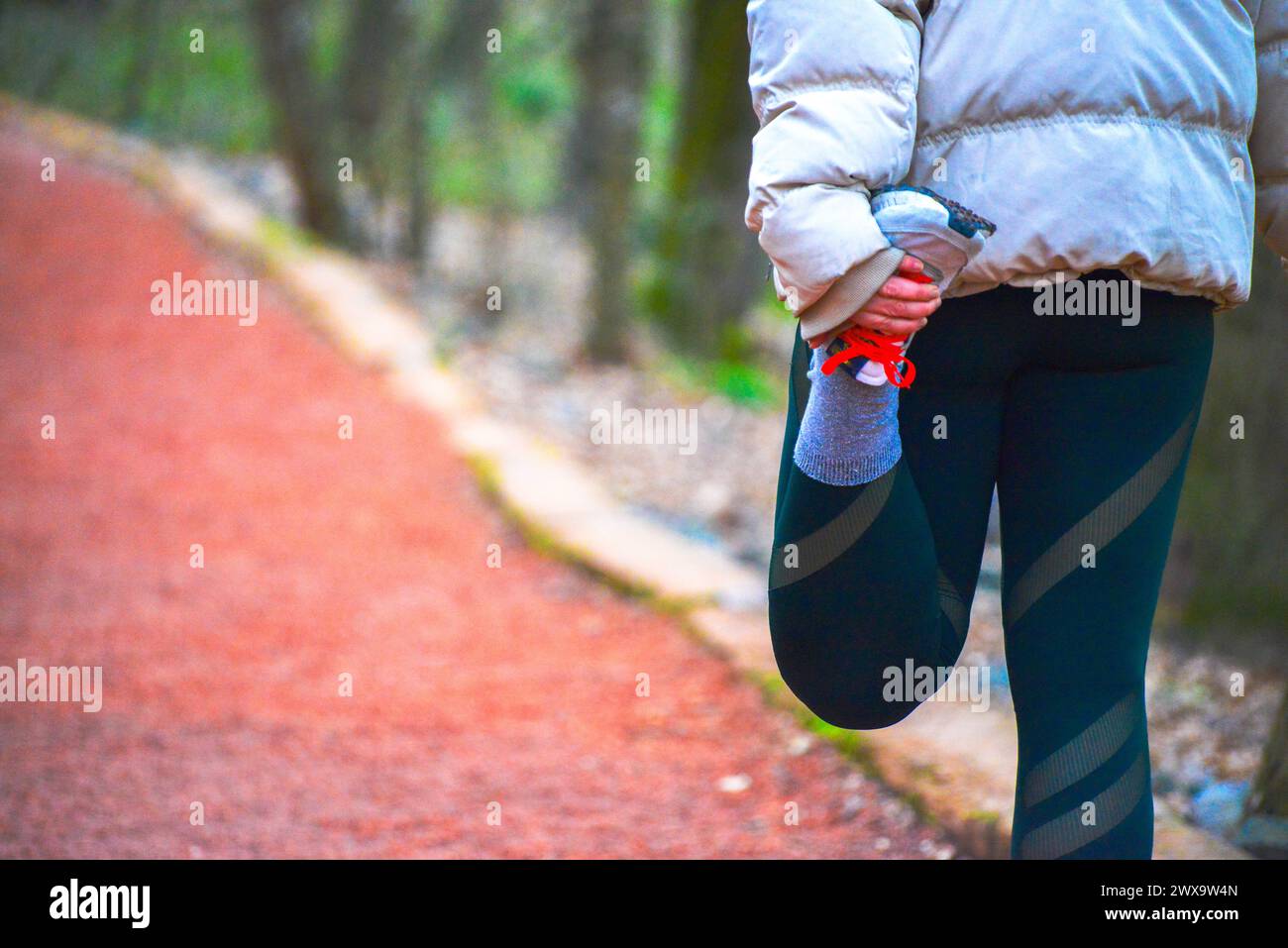 A woman stretching and running on the forest road, embracing the ...