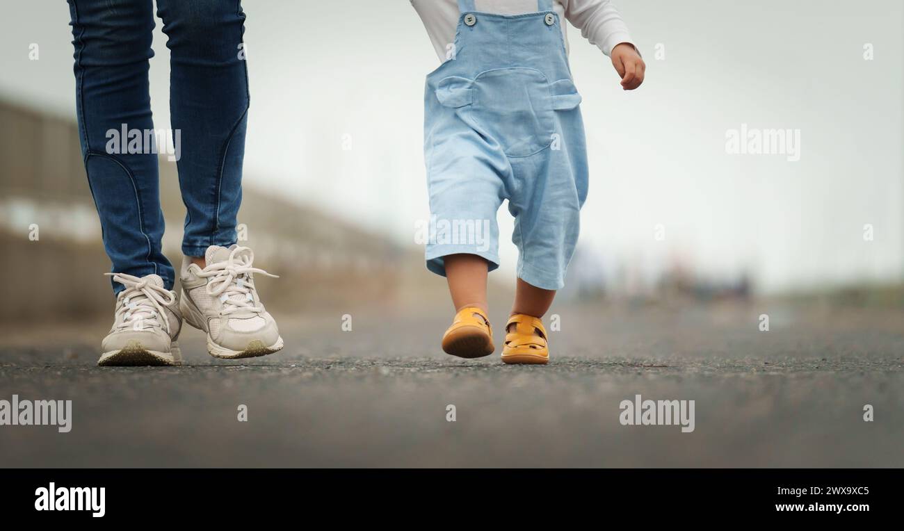 close up leg of infant baby walking on a path with mother helping Stock ...