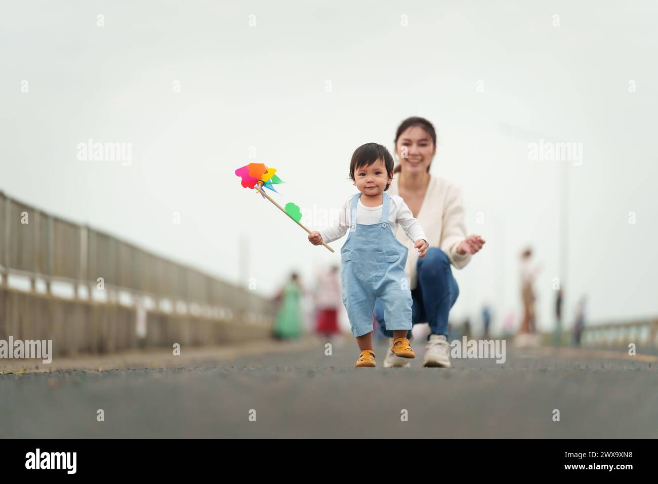 infant baby learn walking first step on a pathway with mother helping ...