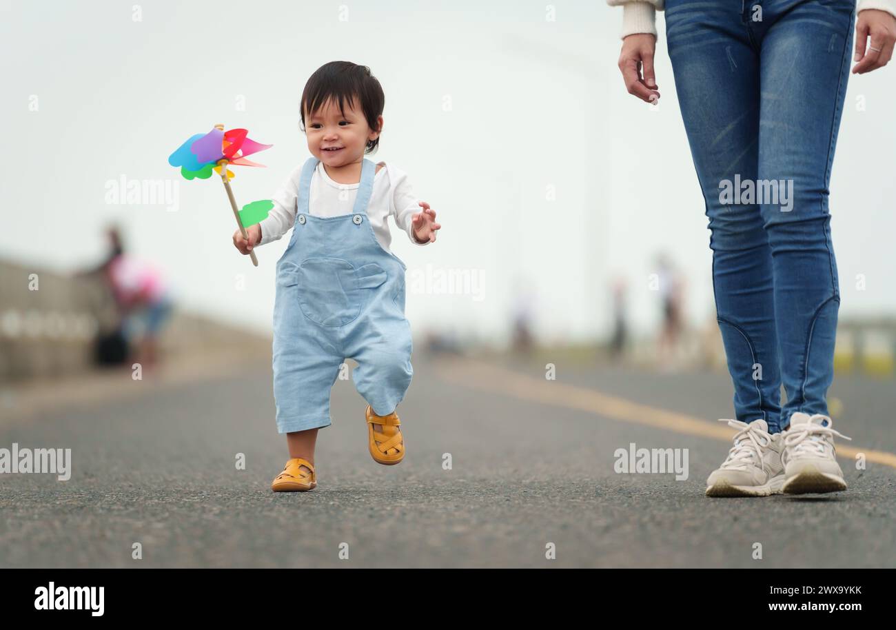 infant baby learn walking first step on a pathway with mother helping ...