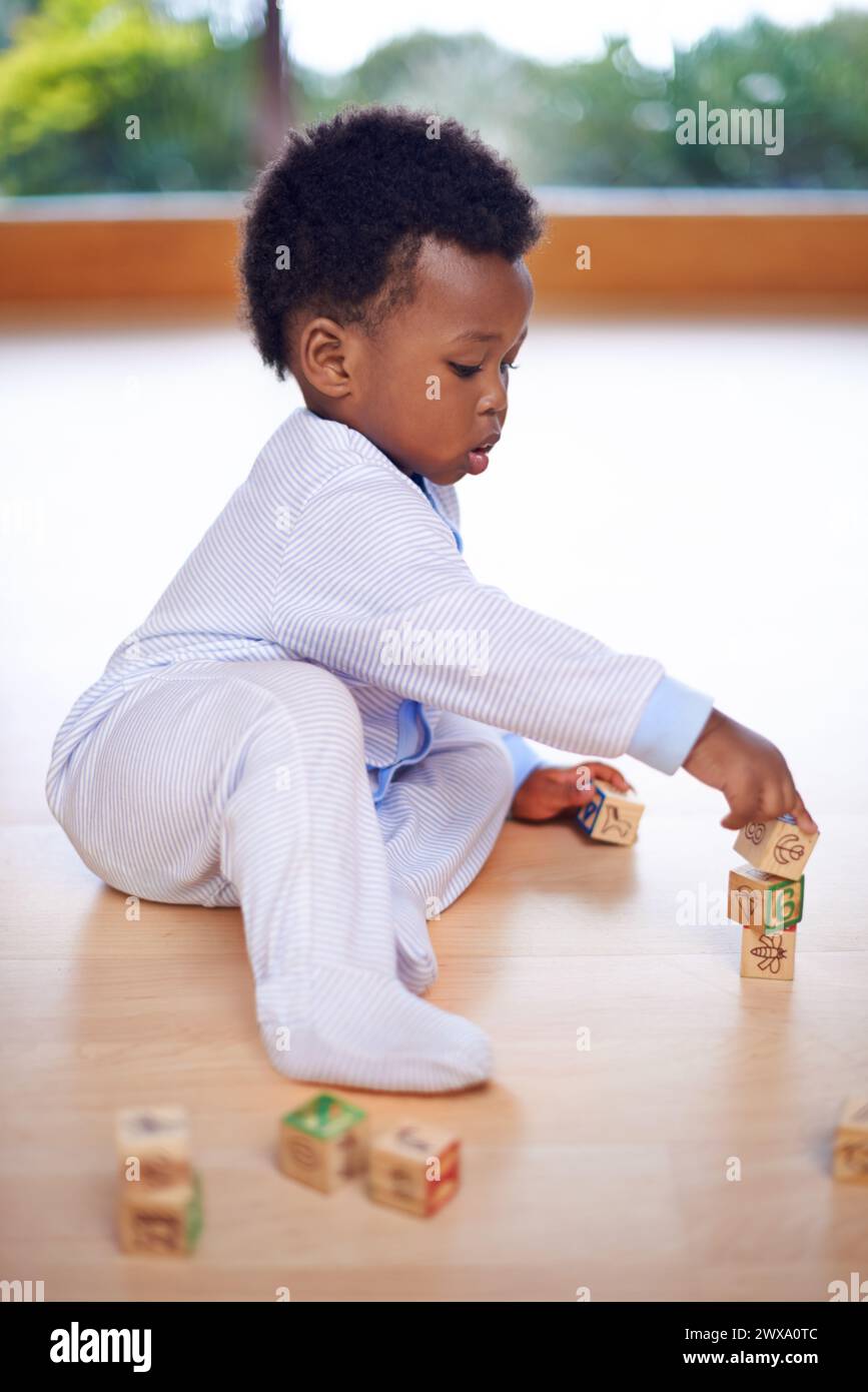 Black baby, playing and wooden blocks in house on floor for child development, growth and motor ...