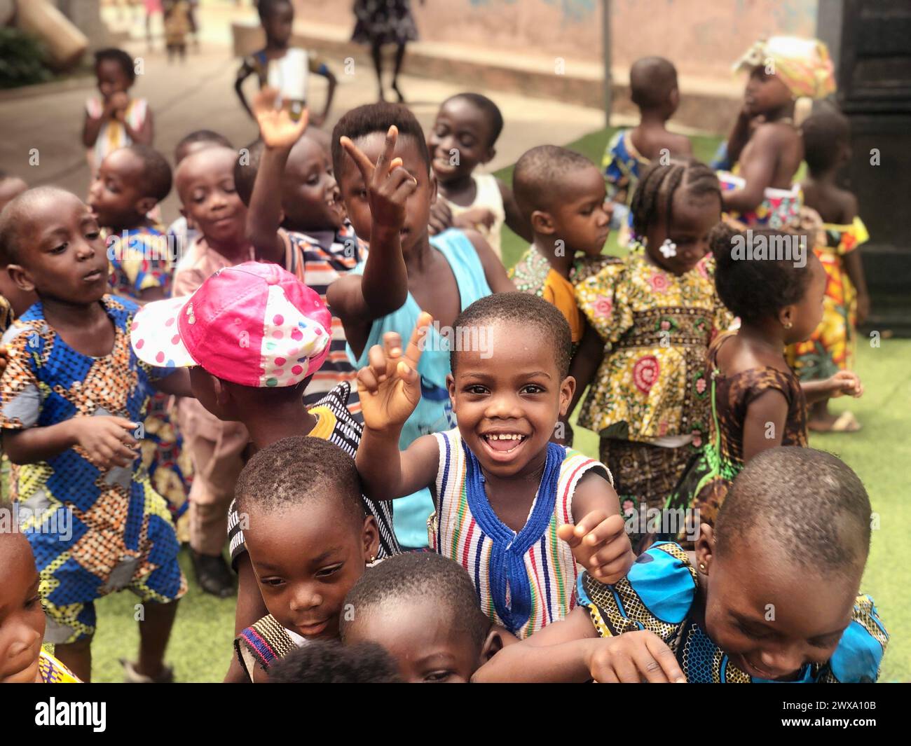 A group of children standing together, happily waving their hands in ...
