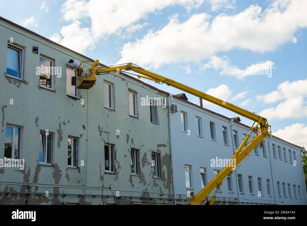 Worker in the basket of a car lift are repairing the facade of ...