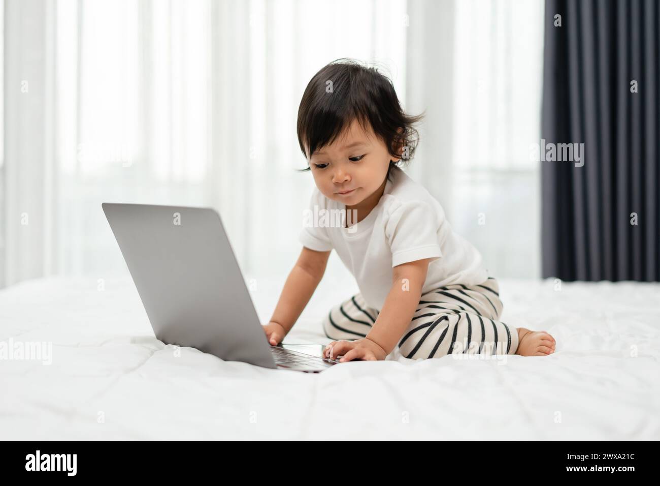 toddler baby using laptop computer on a bed Stock Photo - Alamy