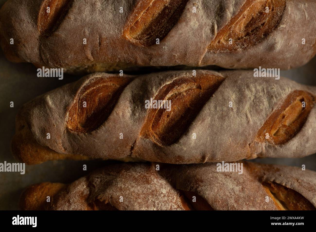 Three baguettes on parchment paper closeup, bread cracks pattern Stock ...