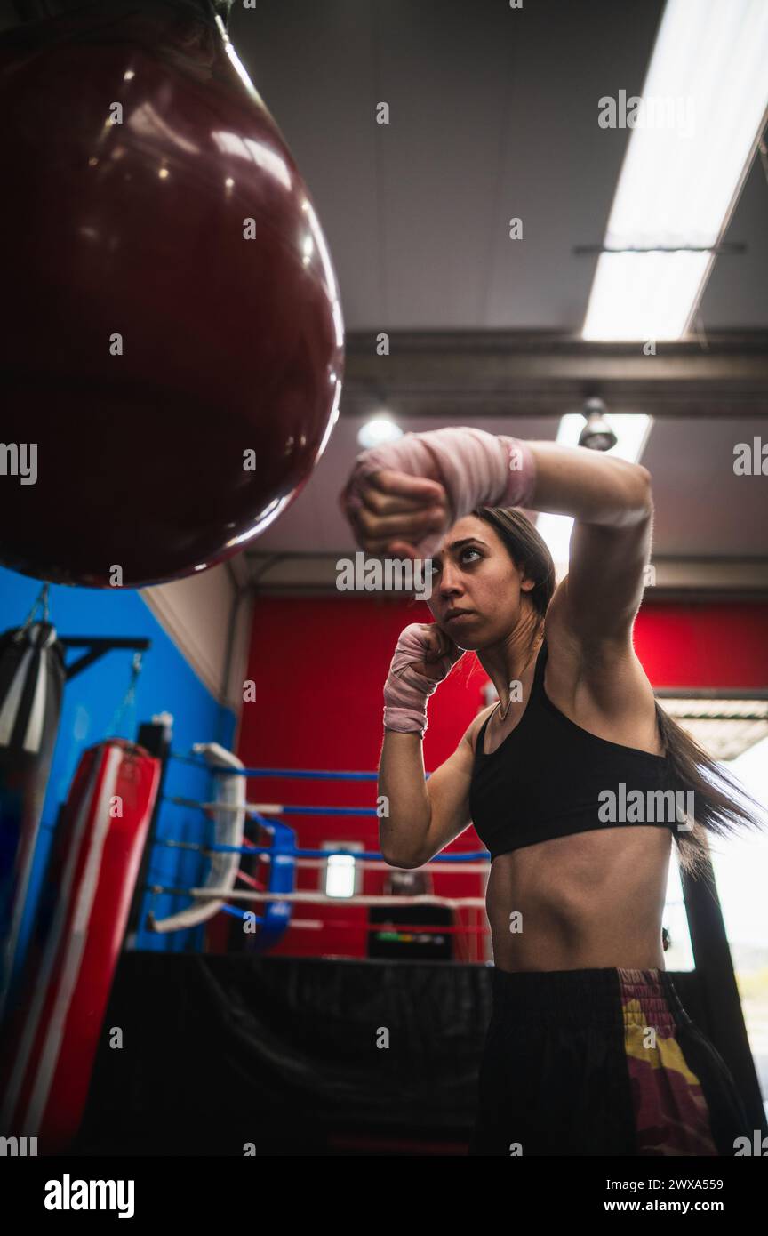 Fit female boxer punching ball wearing straps on wrist in gym Stock ...