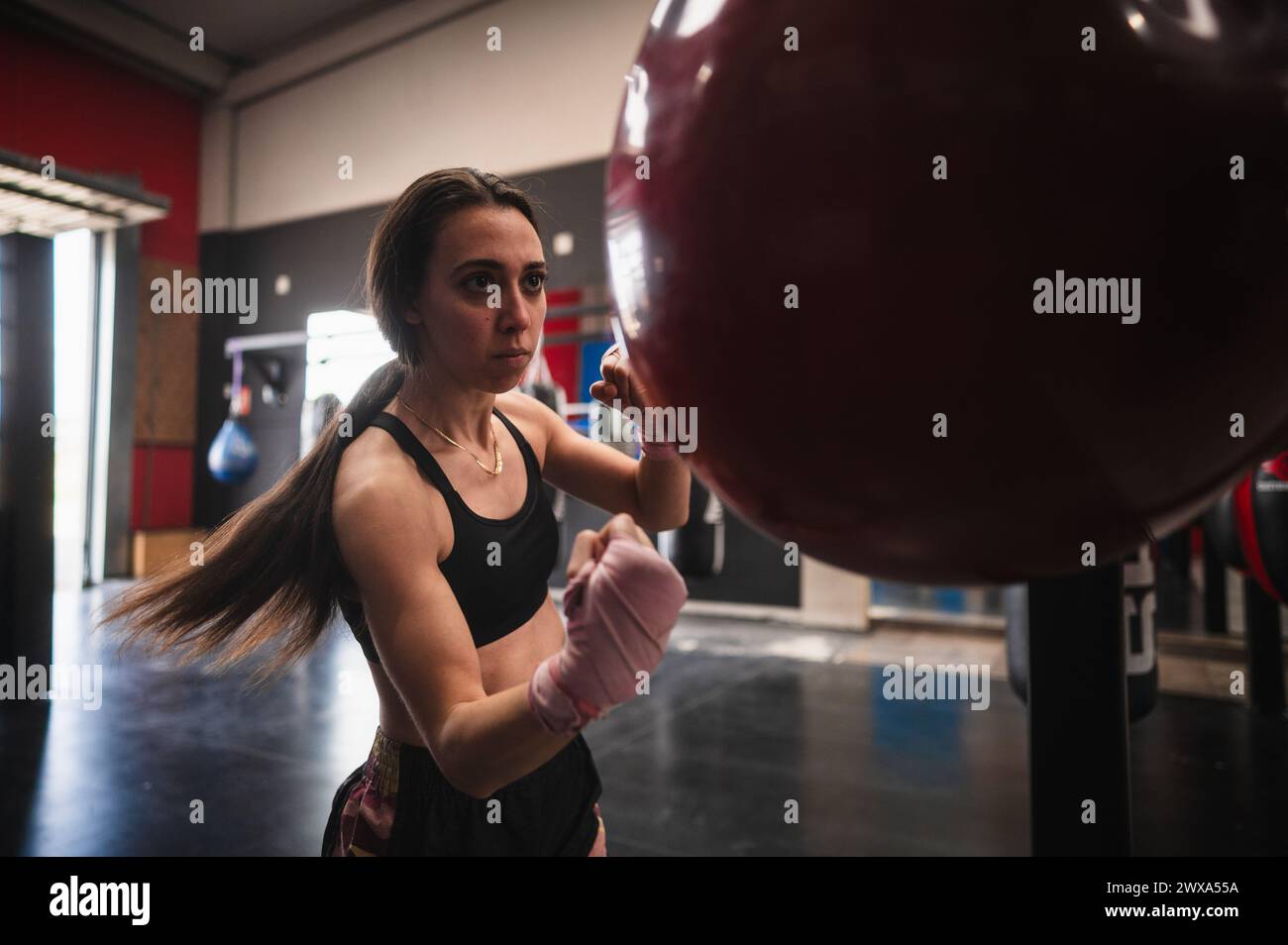 Determined woman training on punching bag in gym Stock Photo - Alamy