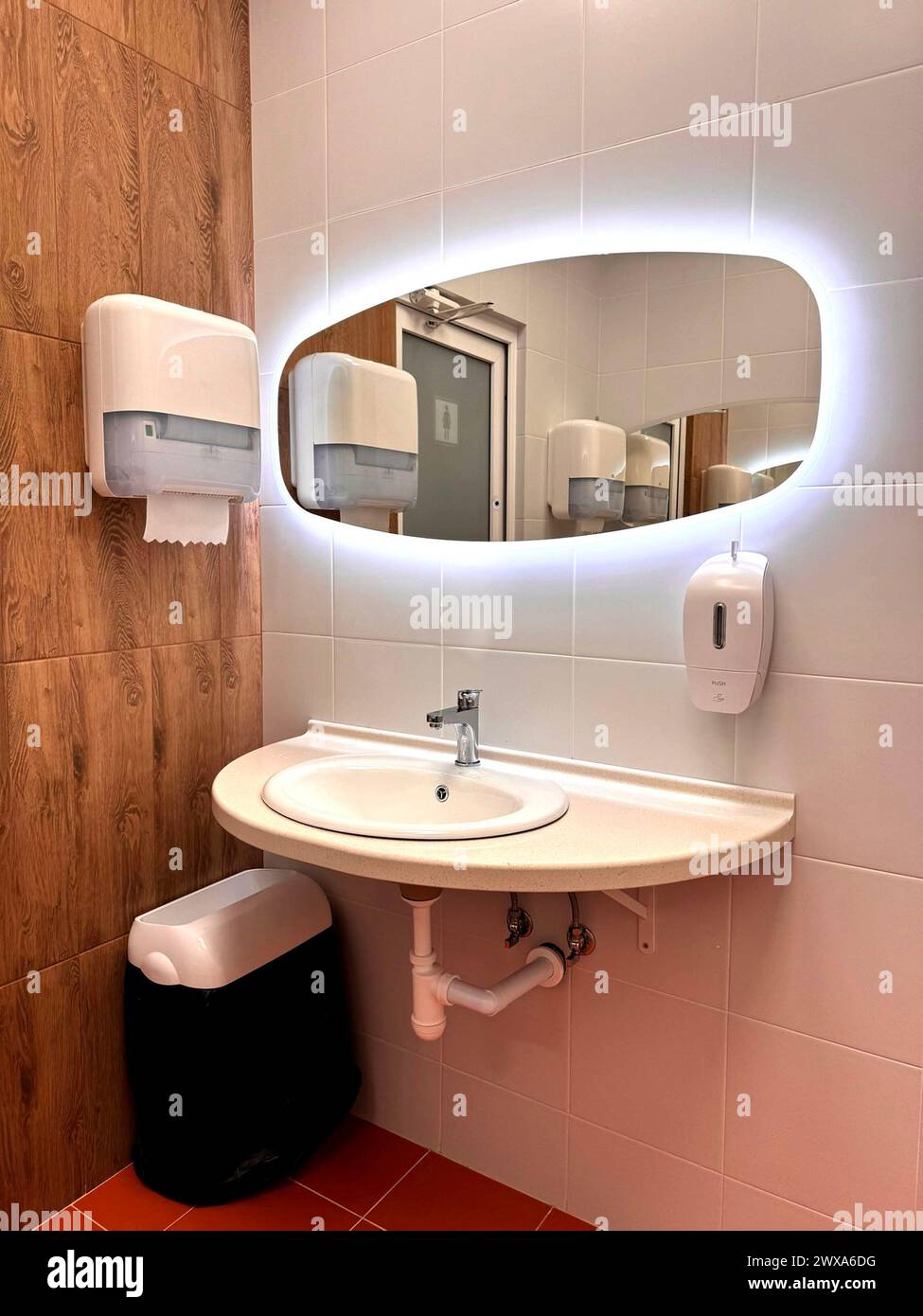 single sink in small public toilet with wall soap dispenser and paper ...