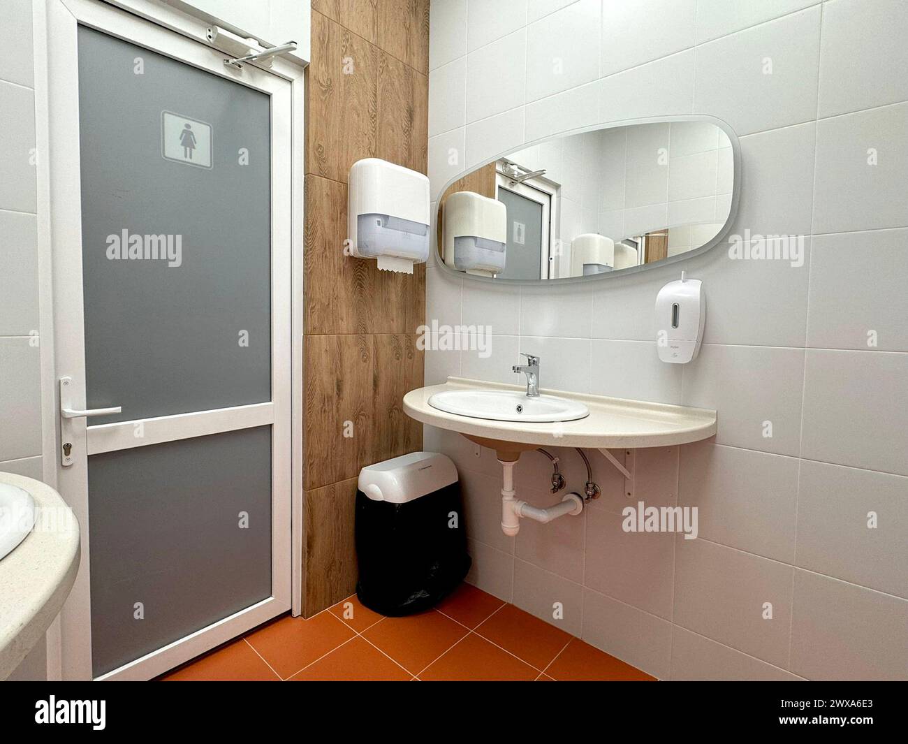 single sink in small public toilet with wall soap dispenser and paper ...