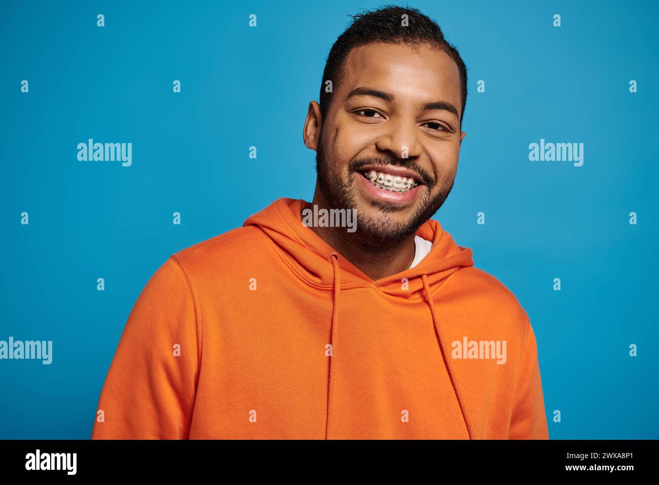 handsome african american young man in orange outfit smiling broadly ...