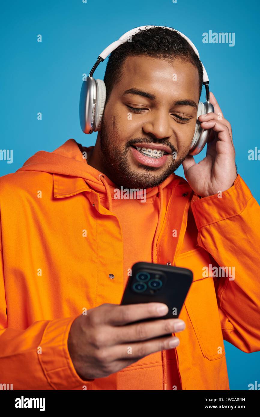 happy african american man in orange outfit and headphones listening to ...