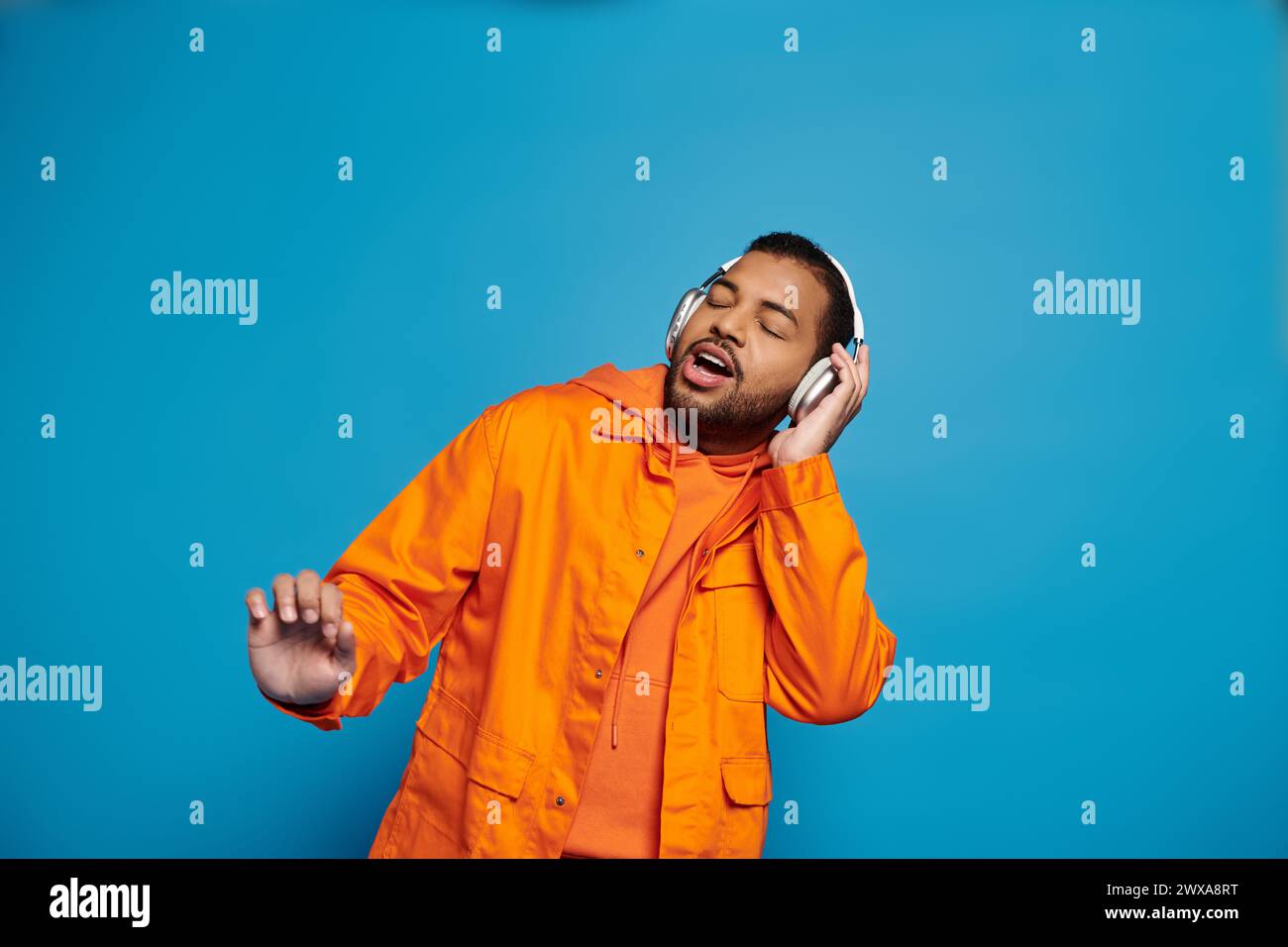 african american man in orange outfit and headphones singing with ...