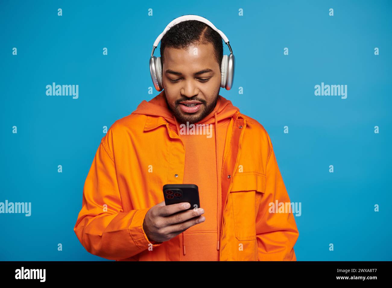 african american guy in orange outfit and headphones scrolling in ...