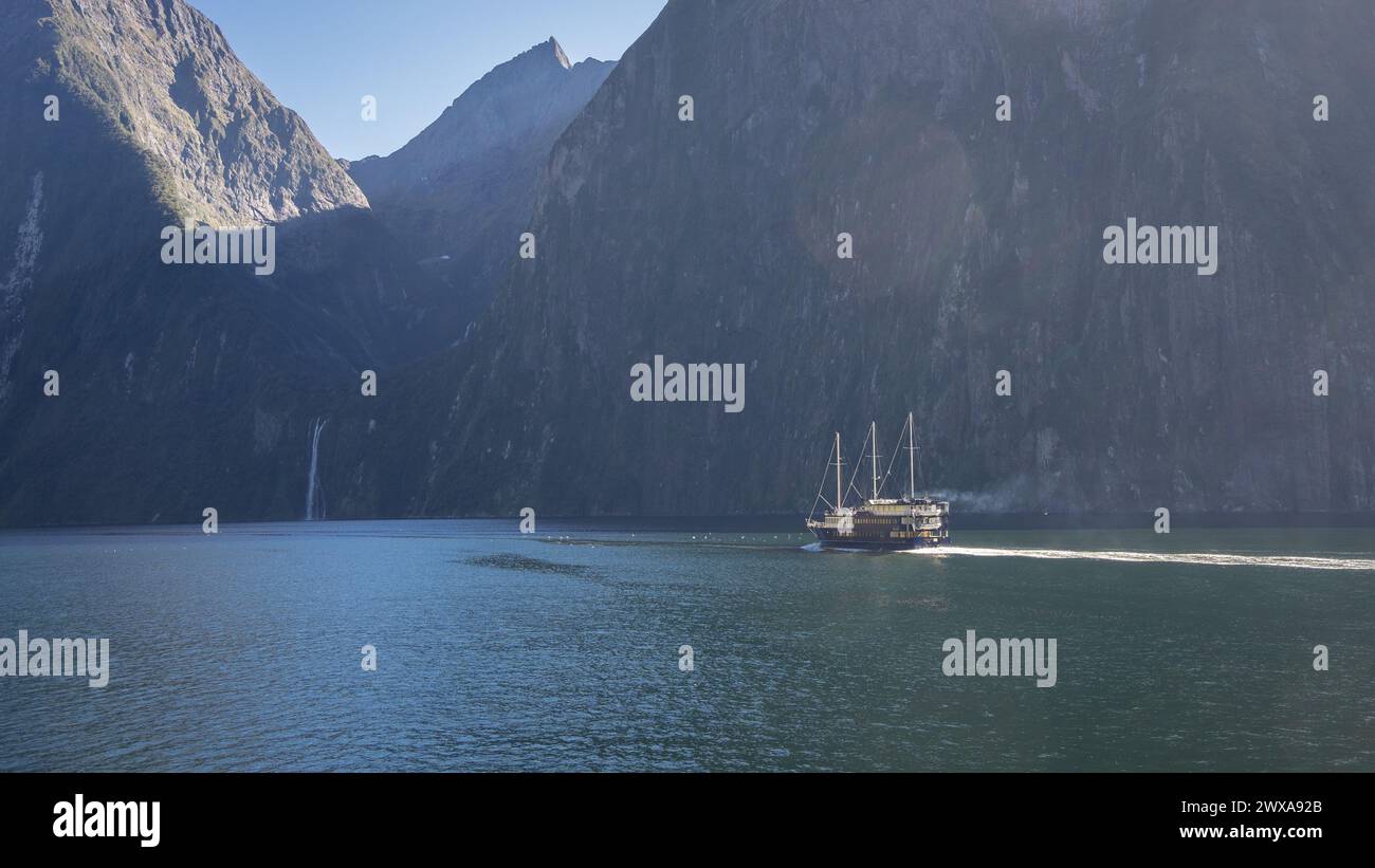 Boat sailing through fjord with steep rocky walls and waterfall in ...