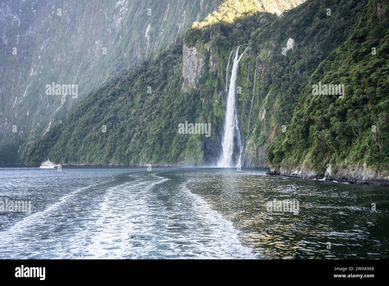 Tourist sightseeing boat approaching big waterfall in fjord falling ...