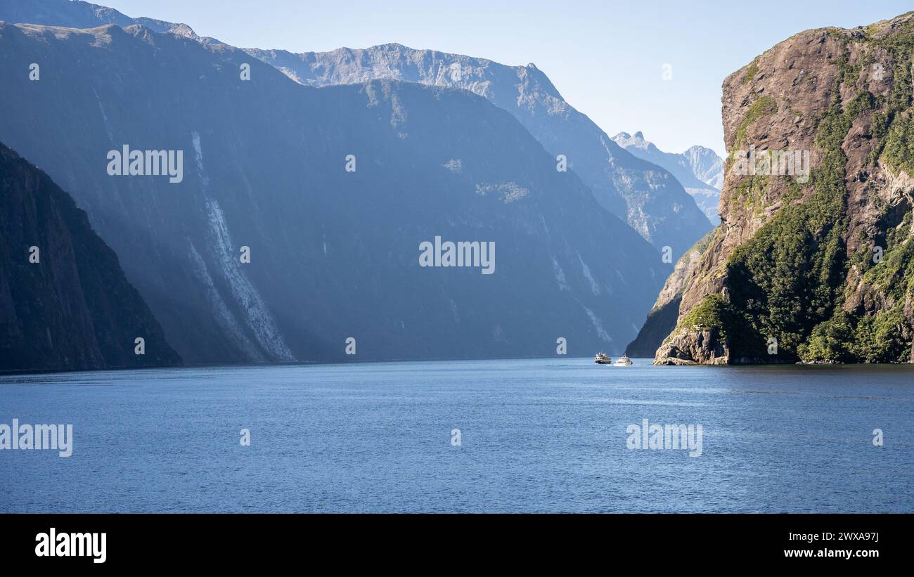 Tourist sightseeing boats sailing through fjord with steep rocky walls ...