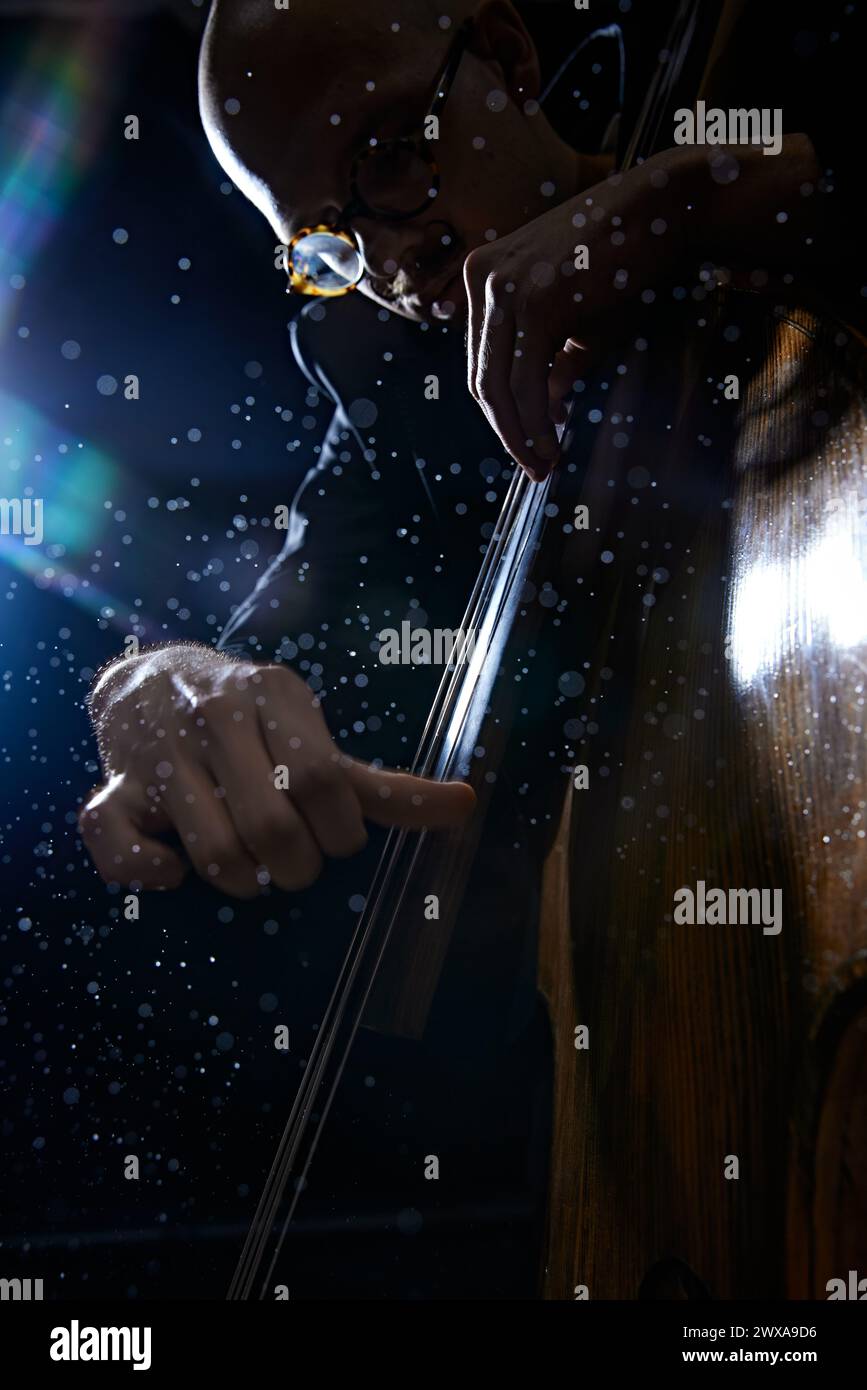 Male musician playing double bass against black background with lights ...