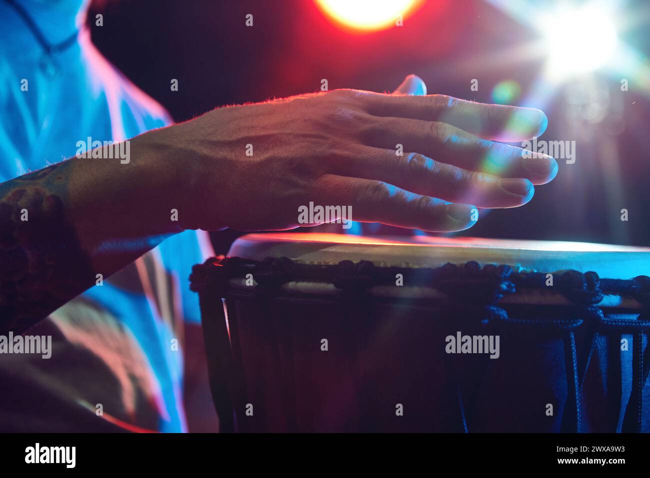 Close-up of male hands, musician playing bongo drums on dark background ...
