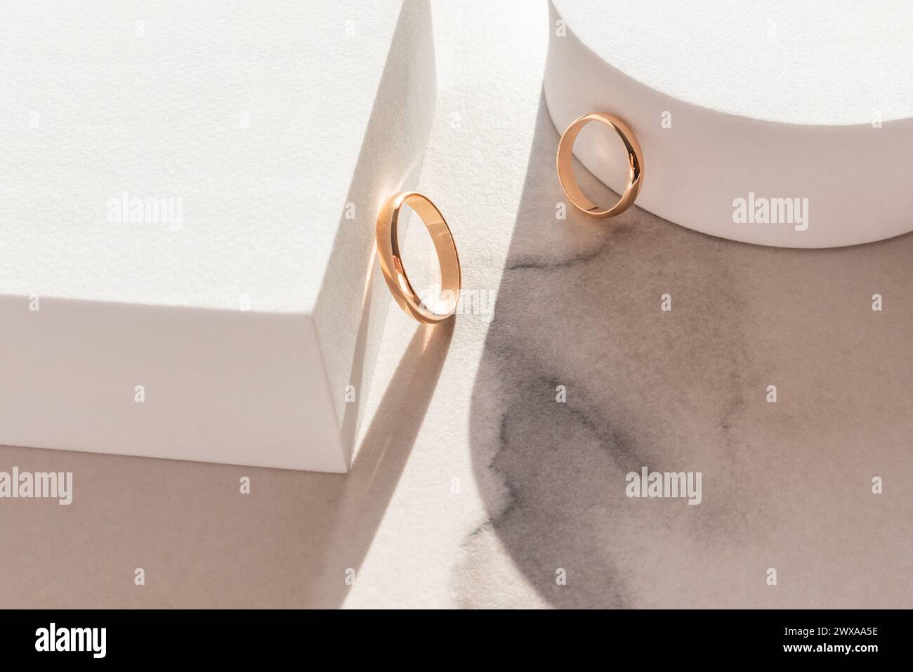 Wedding arrangement of two gold wedding rings on a white marble ...