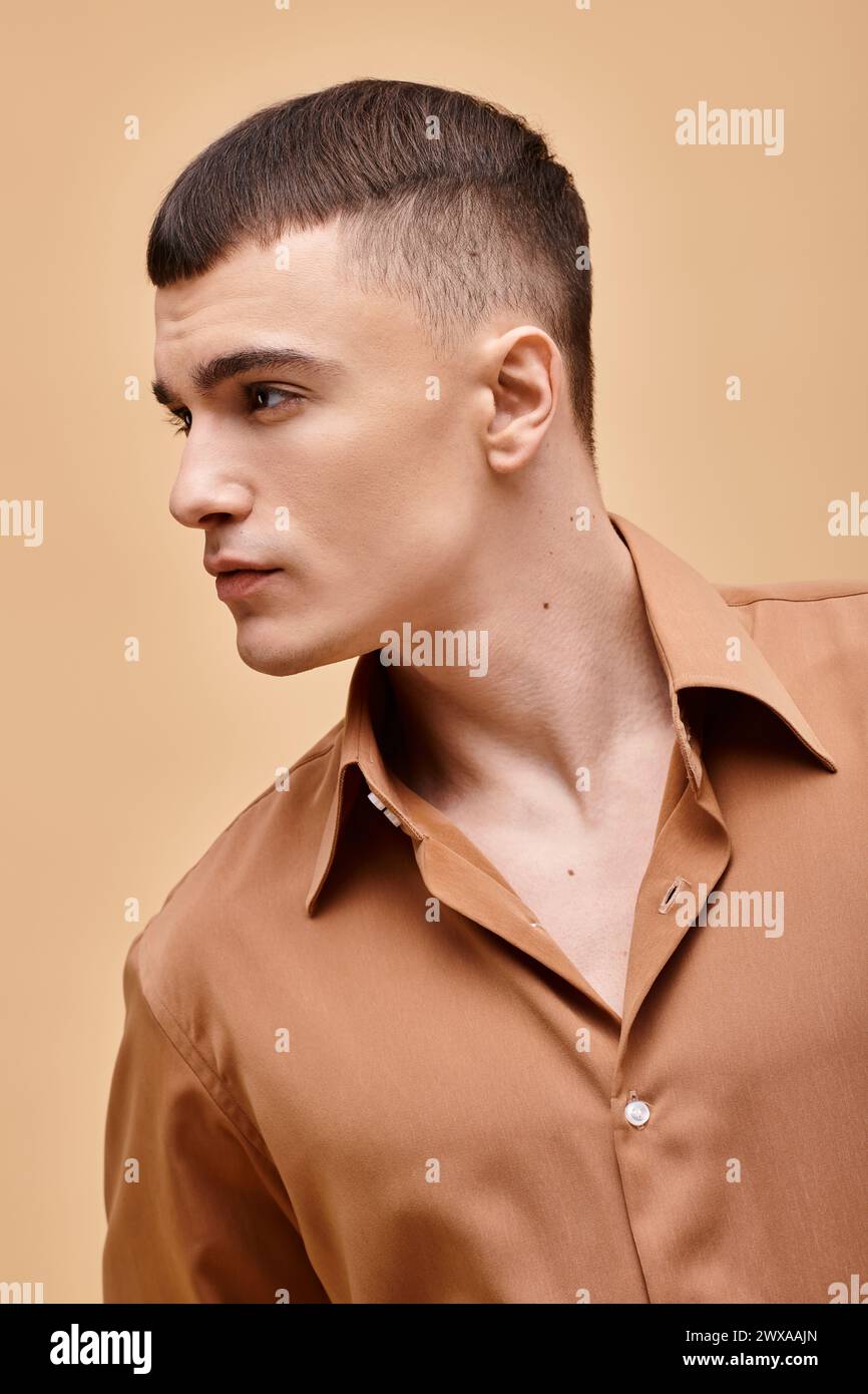 Portrait of young handsome man in beige shirt looking away on peachy ...