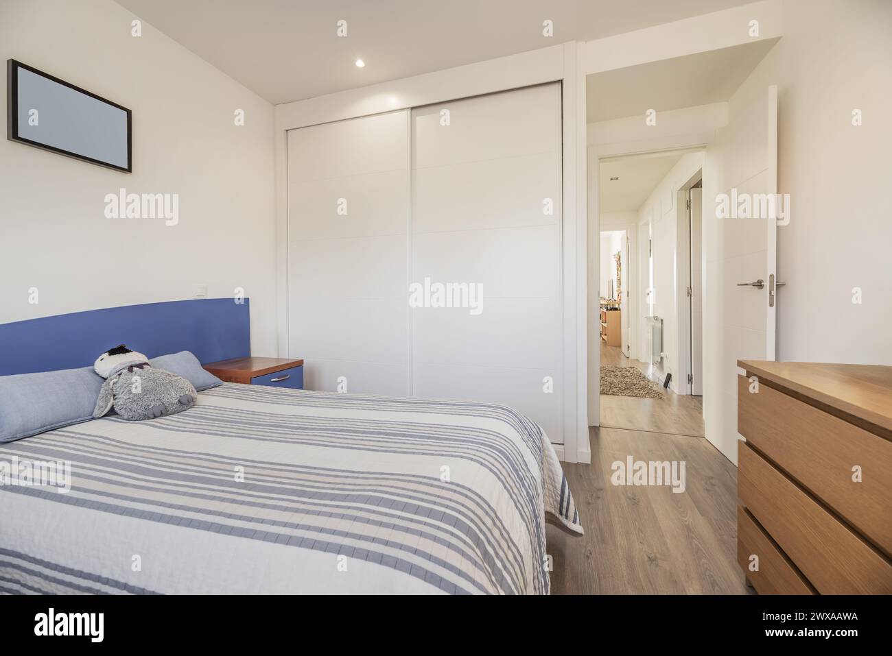 Bedroom with double bed with tattered patterned bedspread, light wood ...