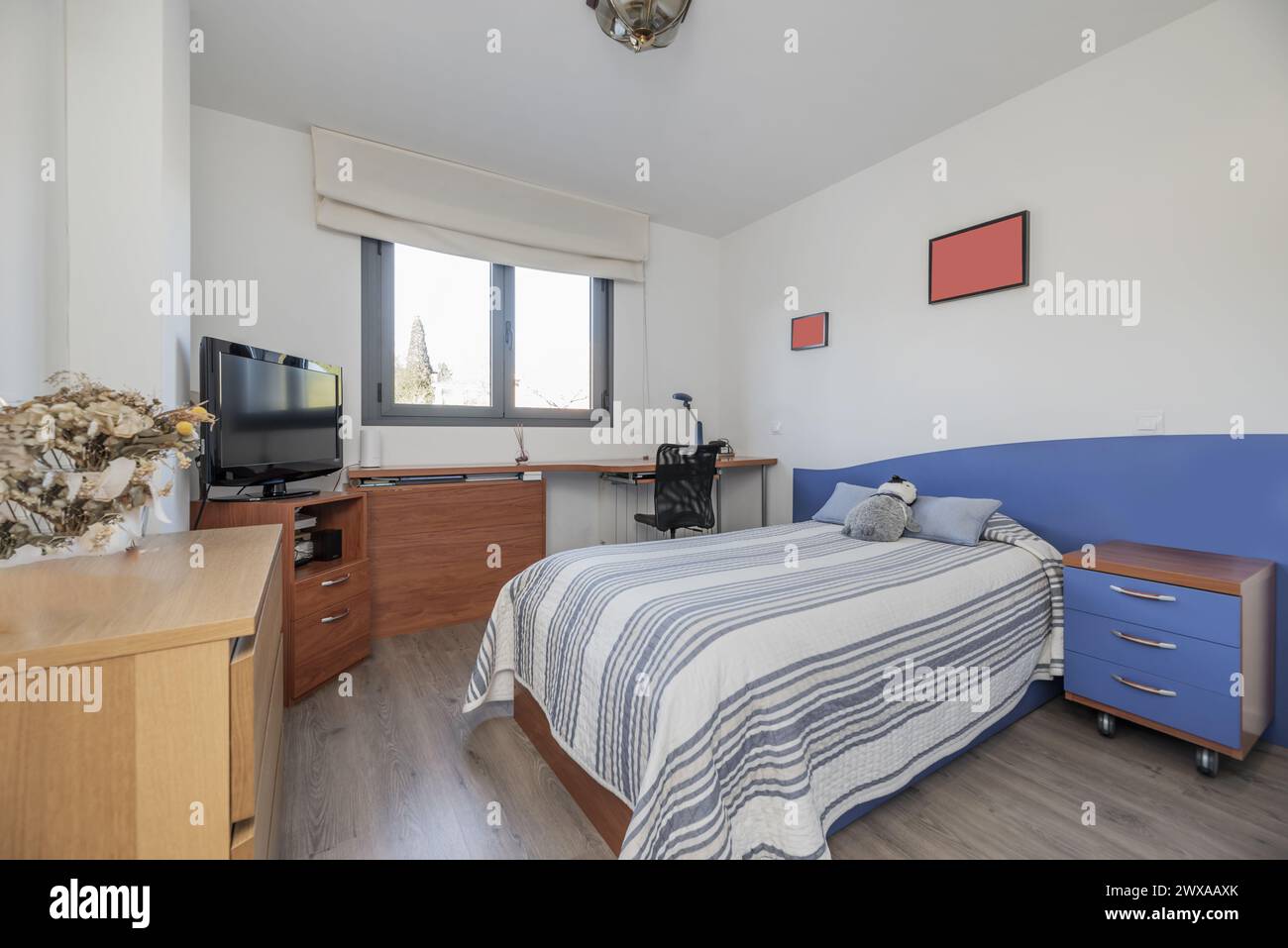 Bedroom with double bed with tattered patterned bedspread, light wooden ...