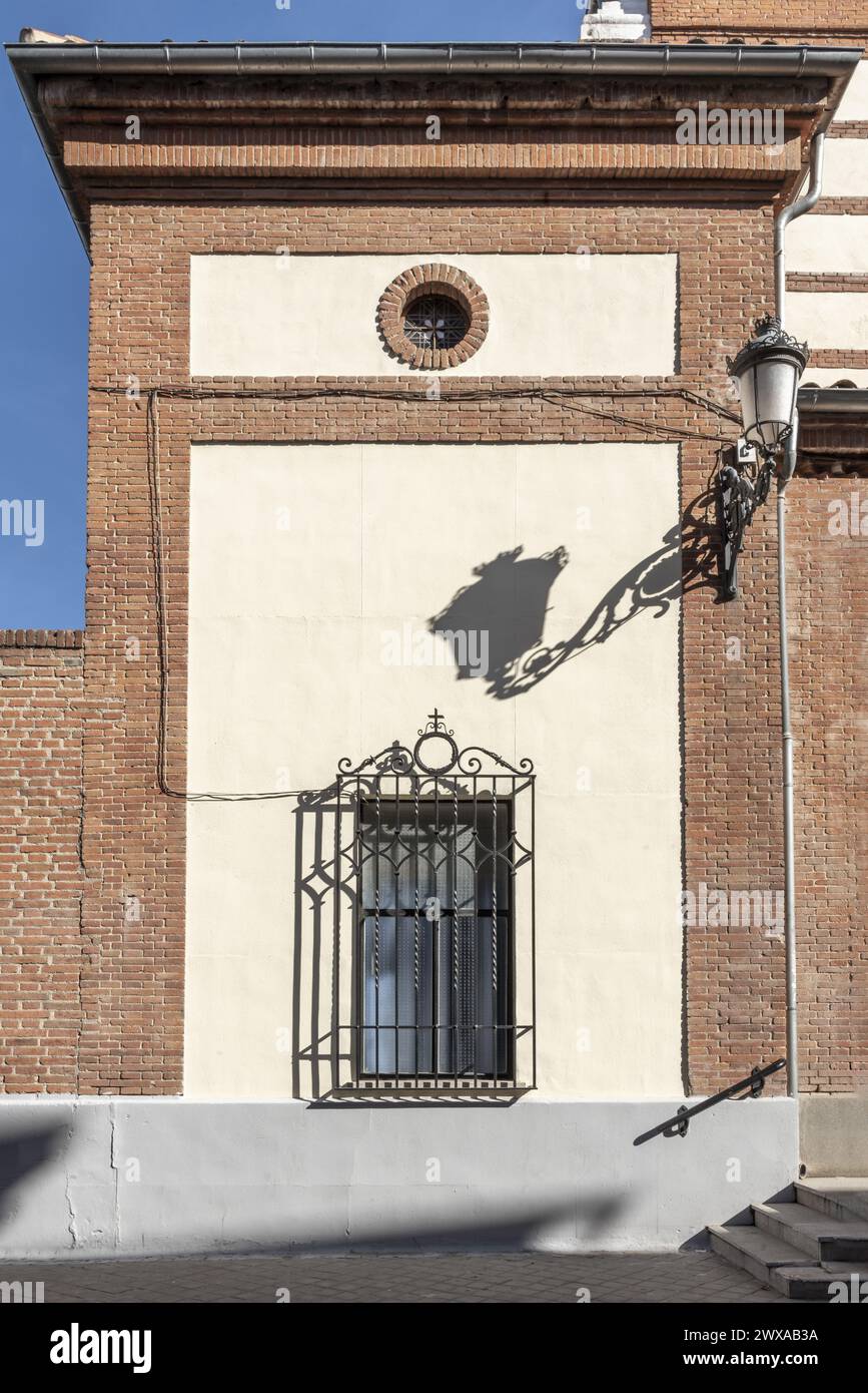 Detail of church facade with small window with black metal wrought iron ...