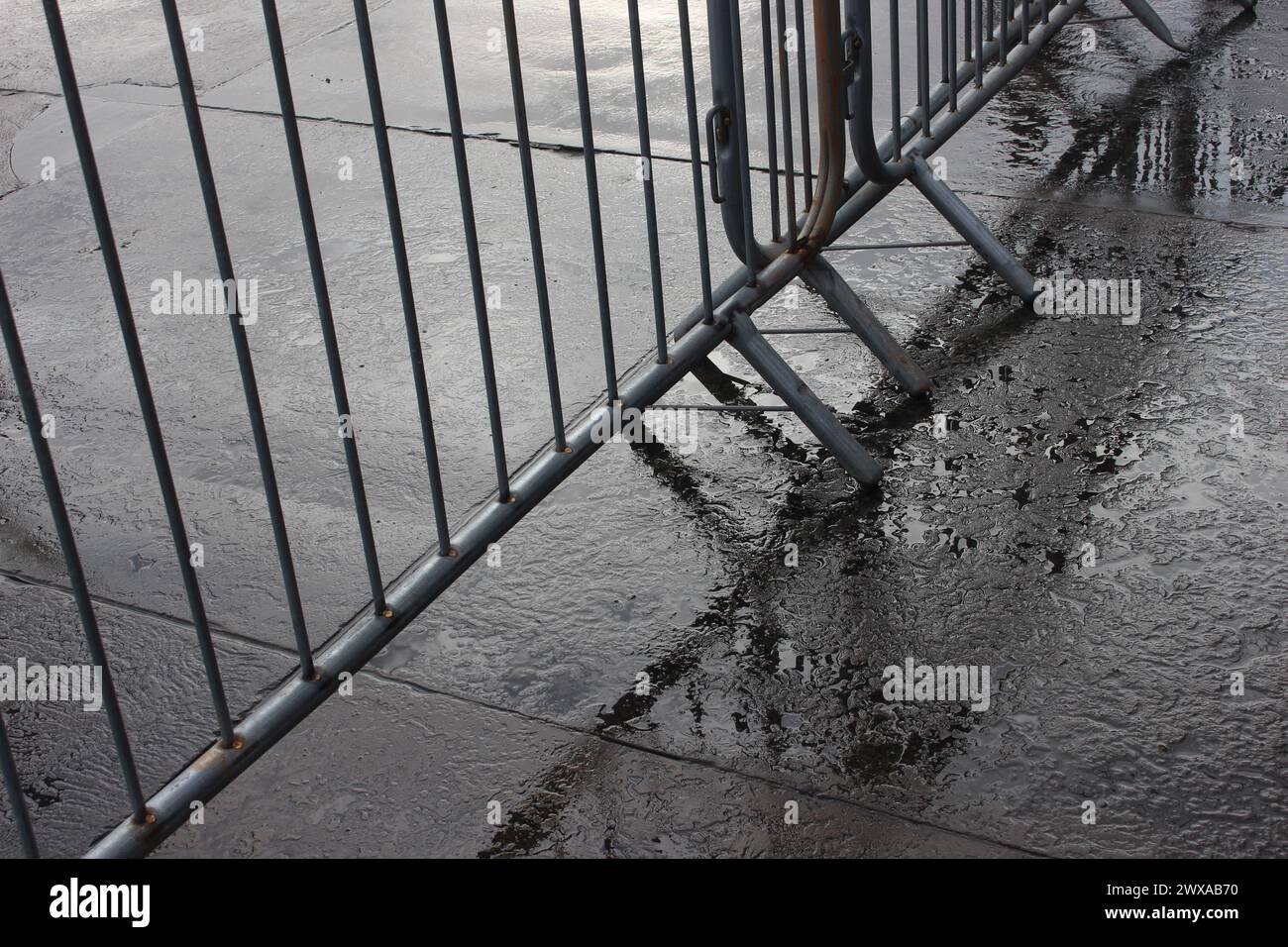 A photograph of security barriers in an urban location. Wet pavement ...
