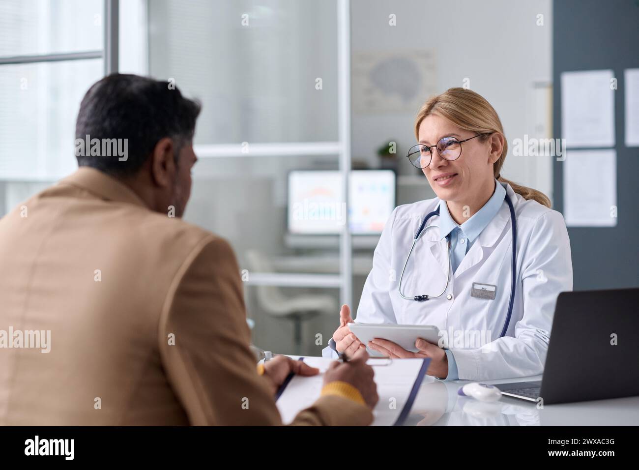 Portrait of smiling female doctor talking to Middle eastern man during ...
