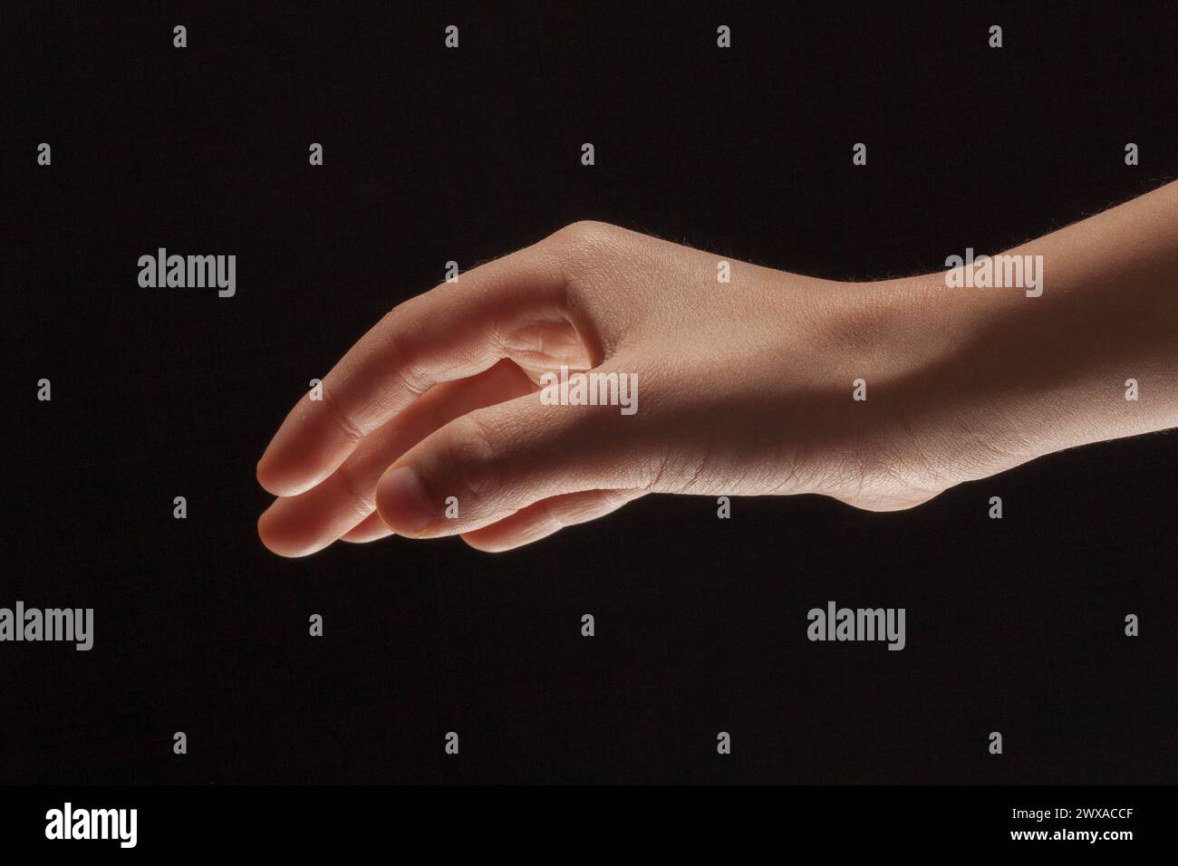 A boy's delicate right hand with palm facing up on a black background ...