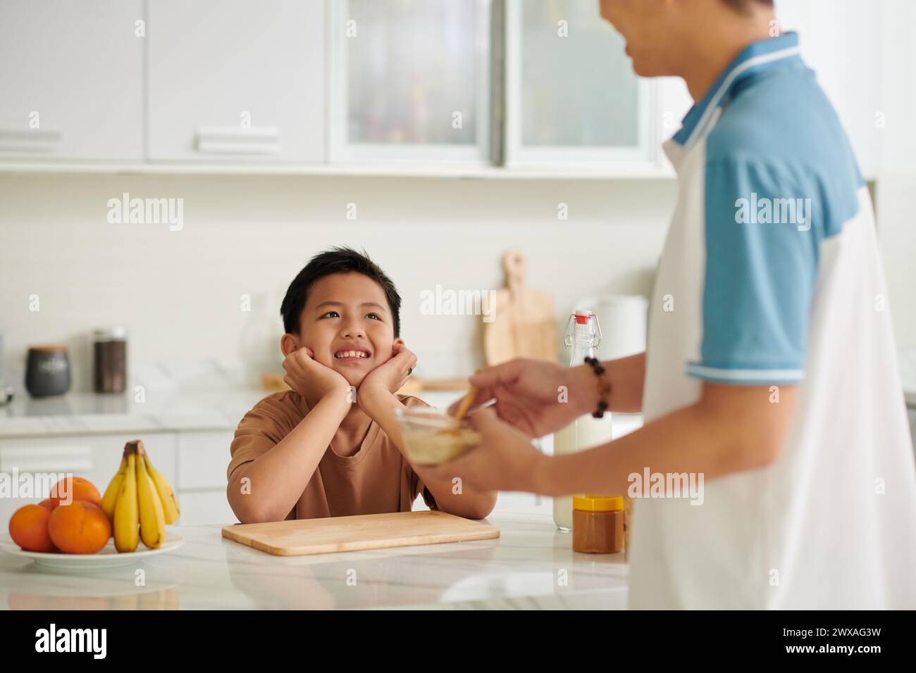 Happy kid looking at father making breakfast Stock Photo - Alamy